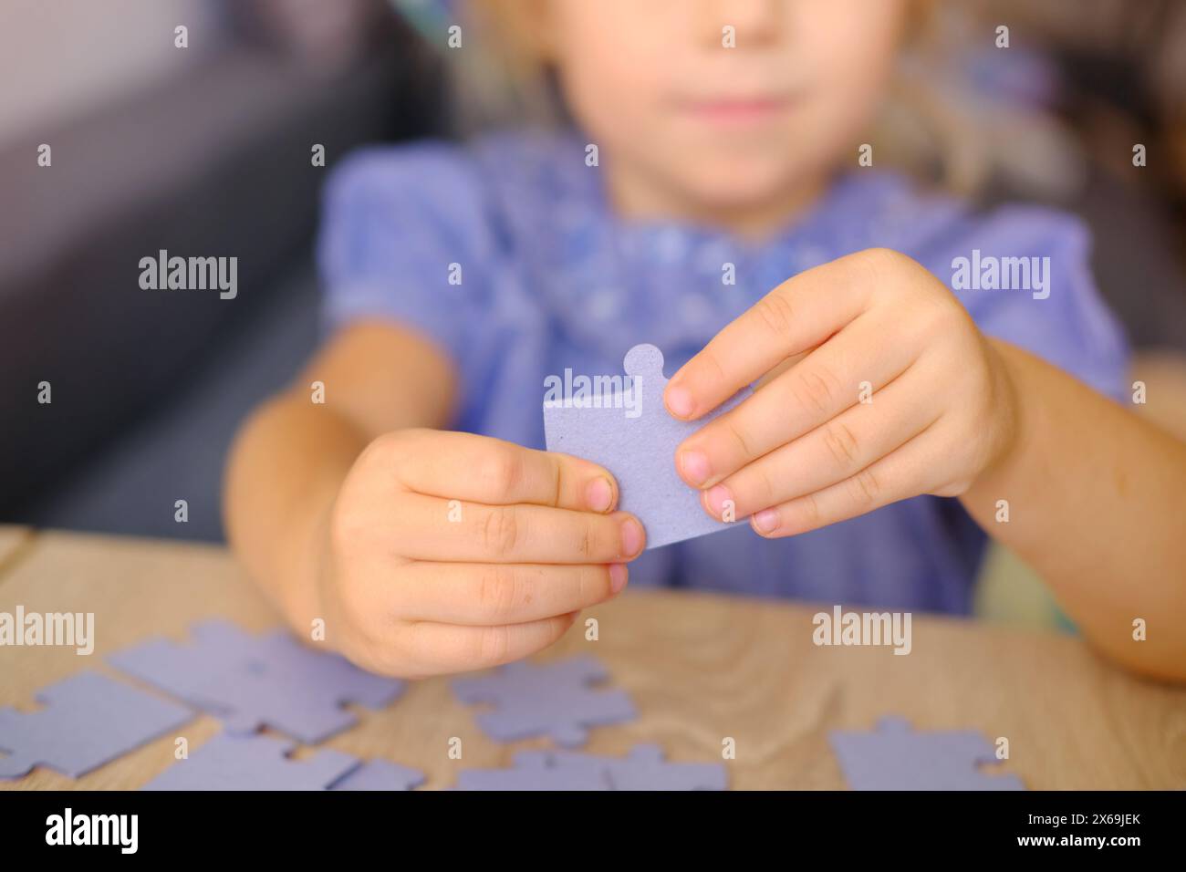 little child assembling puzzles, sorting cardboard pieces by shape ...