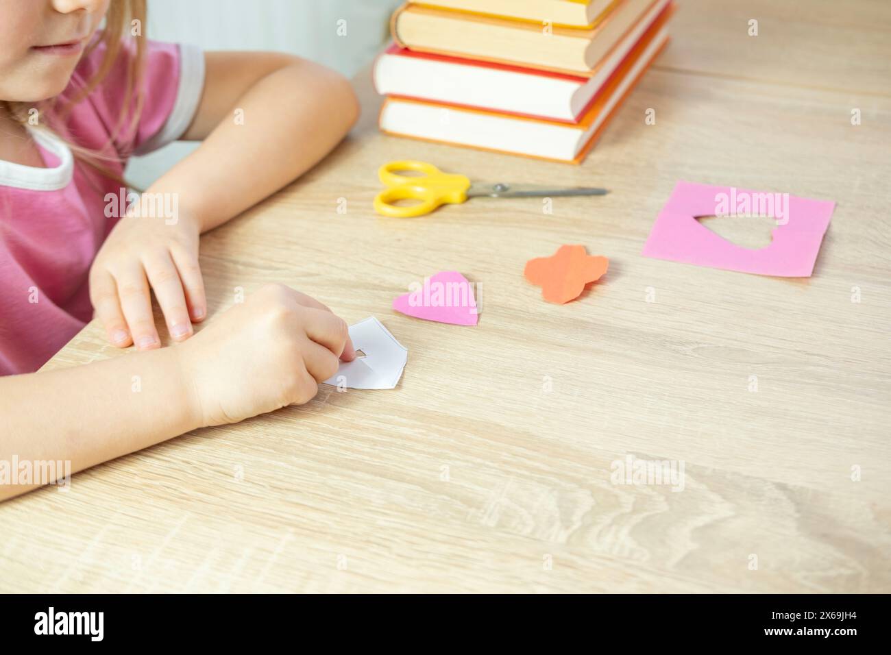 preschooler girl practicing scissor skills by cutting out shapes such ...