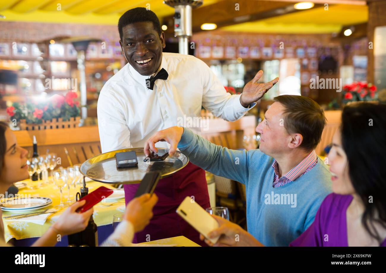 African American waiter brought mobile phones on the tray of restaurant ...