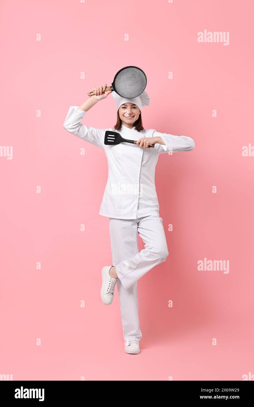 Professional chef with frying pan and spatula having fun on pink ...