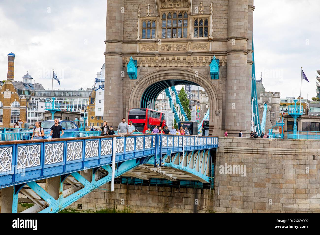 Pedestrians walk across Tower Bridge past a London red double decker ...