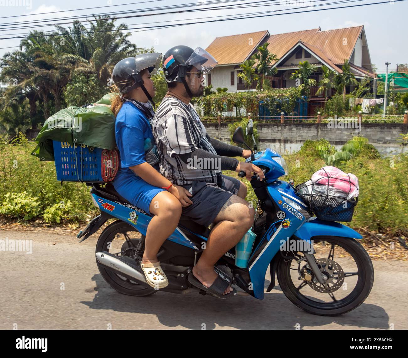 THAILAND, APR 15 2024, A couple is riding a loaded motorcycle along the ...