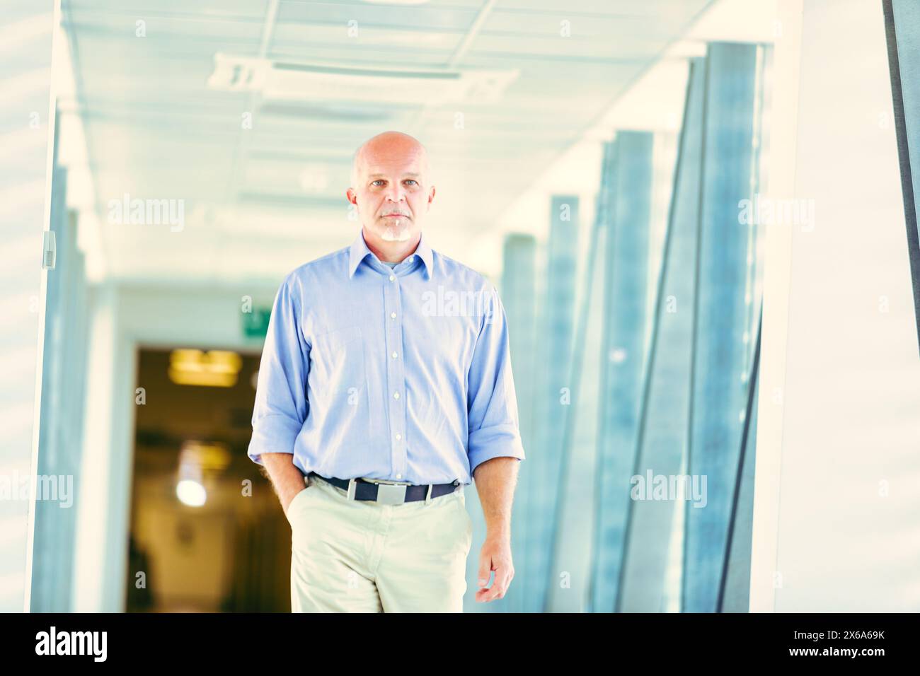 Mature Caucasian man walking towards the camera in a light blue shirt ...