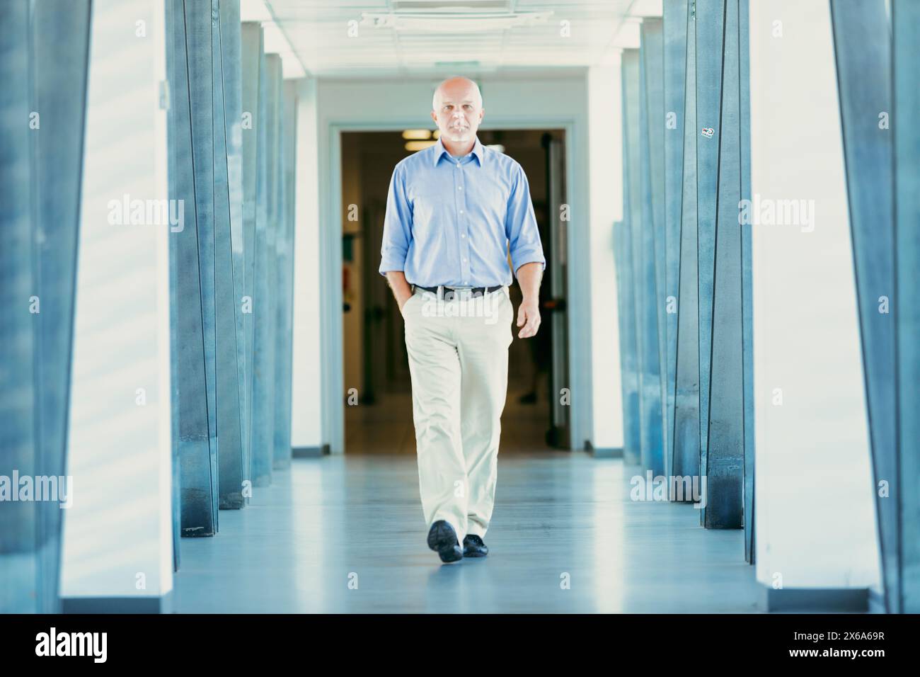Elderly man with a confident walk, dressed in a blue shirt and light ...