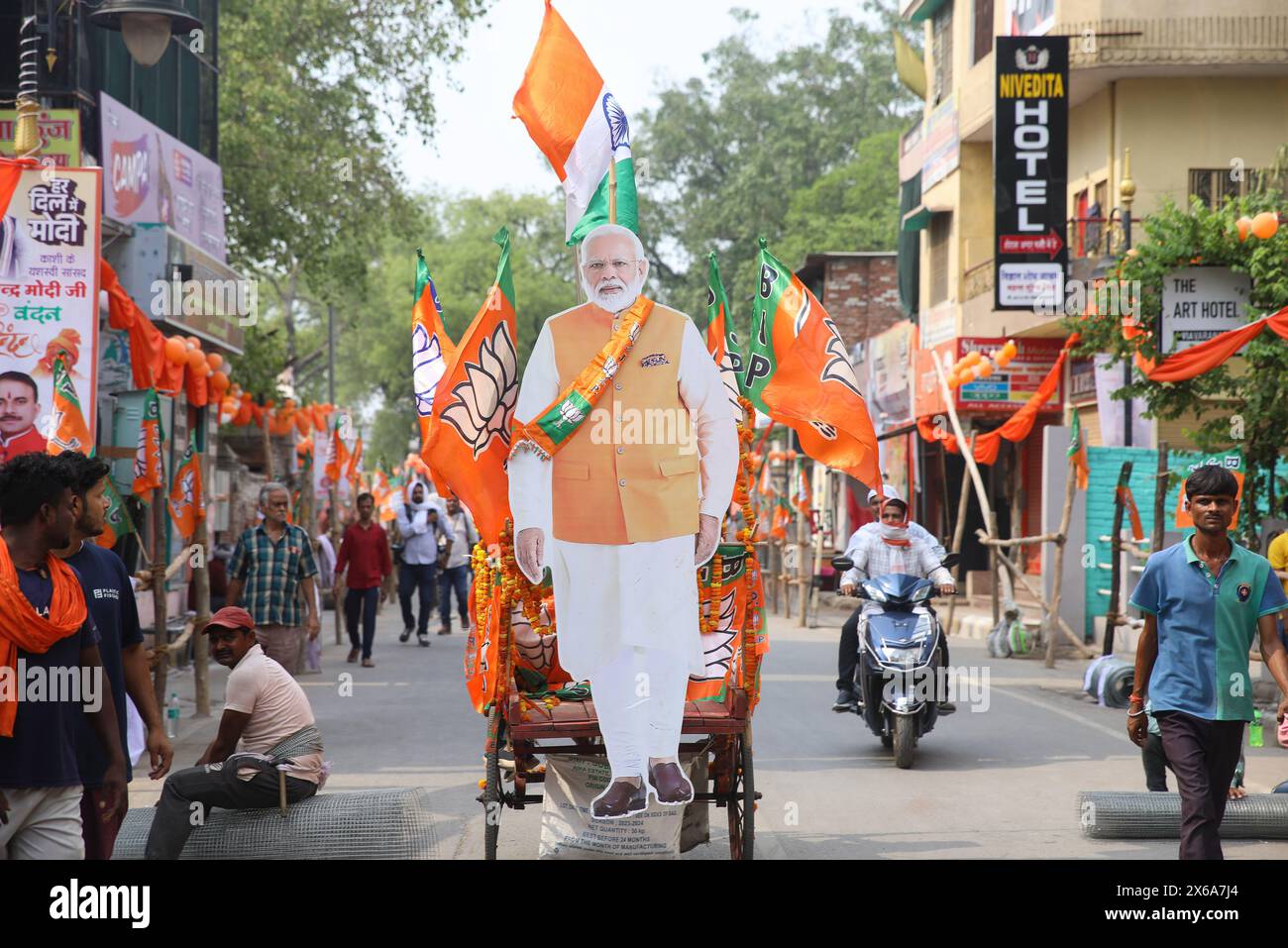Varanasi, India. 13th May, 2024. People walk next to a cutout poster of ...