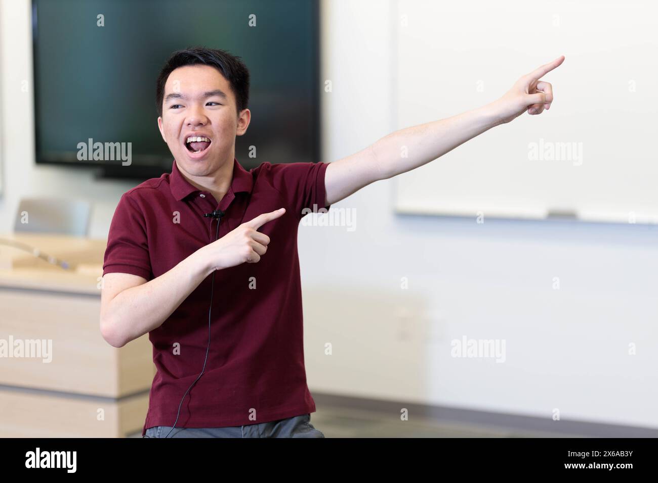 A high school student is making a gesture, pointing up at something in ...
