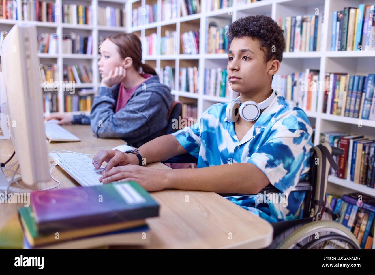 Portrait of teen boy using wheelchair in computer class at school ...