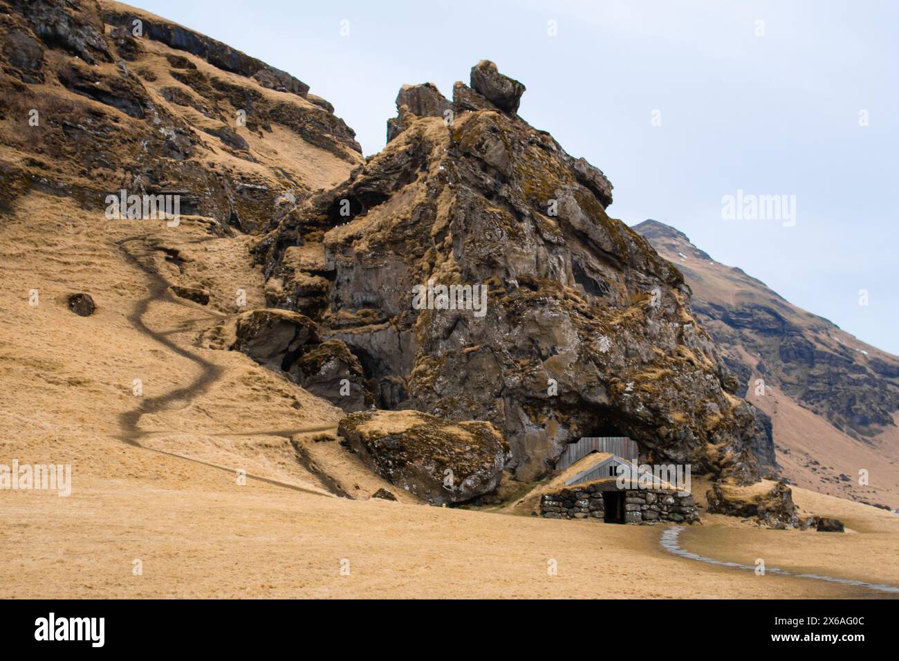 Turf house at foot of Drangurinn Rock in Southern Iceland. Eyjafjll ...