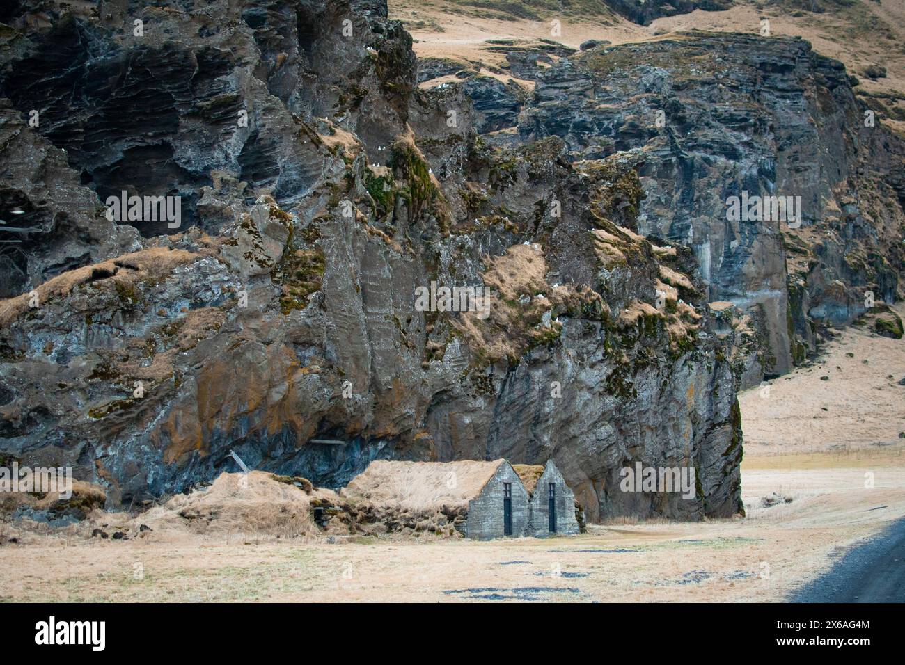 Turf house at foot of Drangurinn Rock in Southern Iceland. Eyjafjll ...