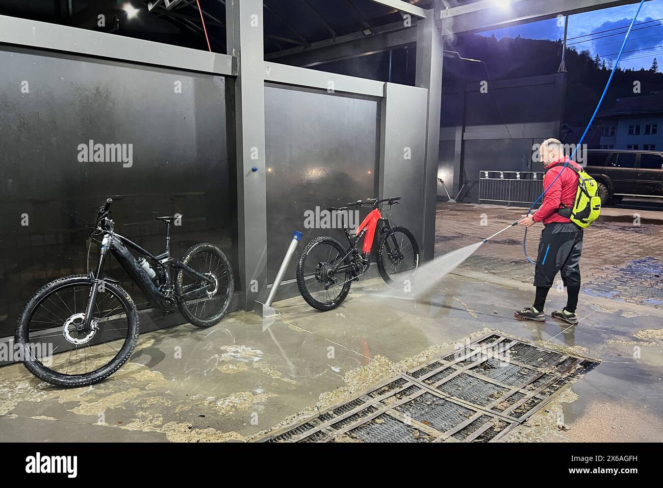 Cyclist using high-pressure water spray to clean two electric mountain ...