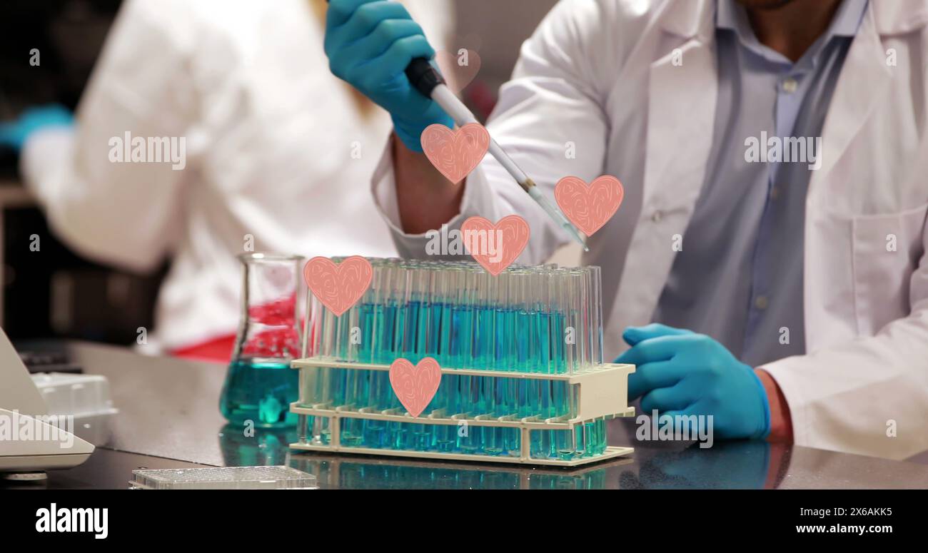 Image of hearts over caucasian male scientist using pipette in lab ...