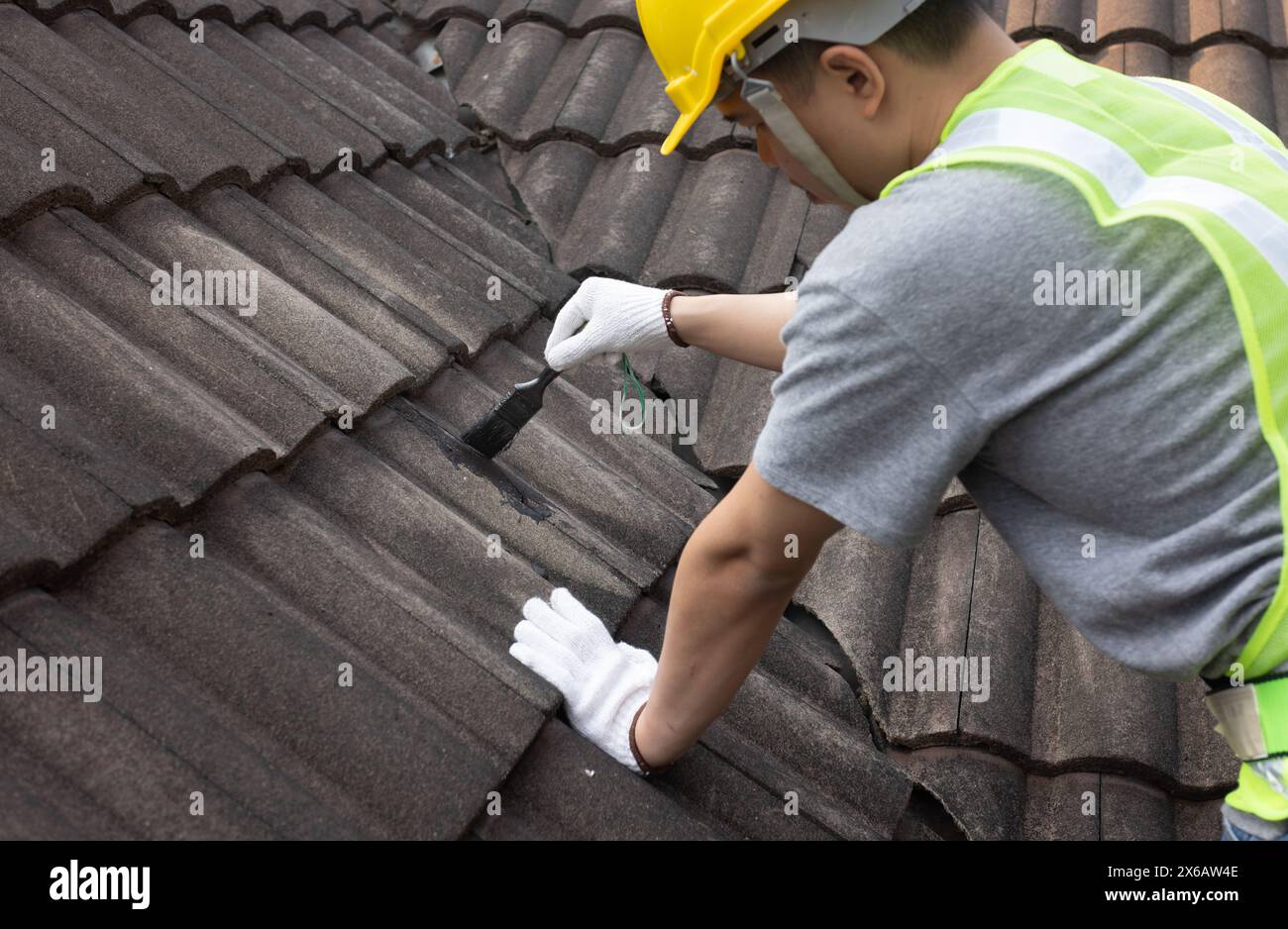 Worker man using waterproof roof coating repair to fix crack of the old ...