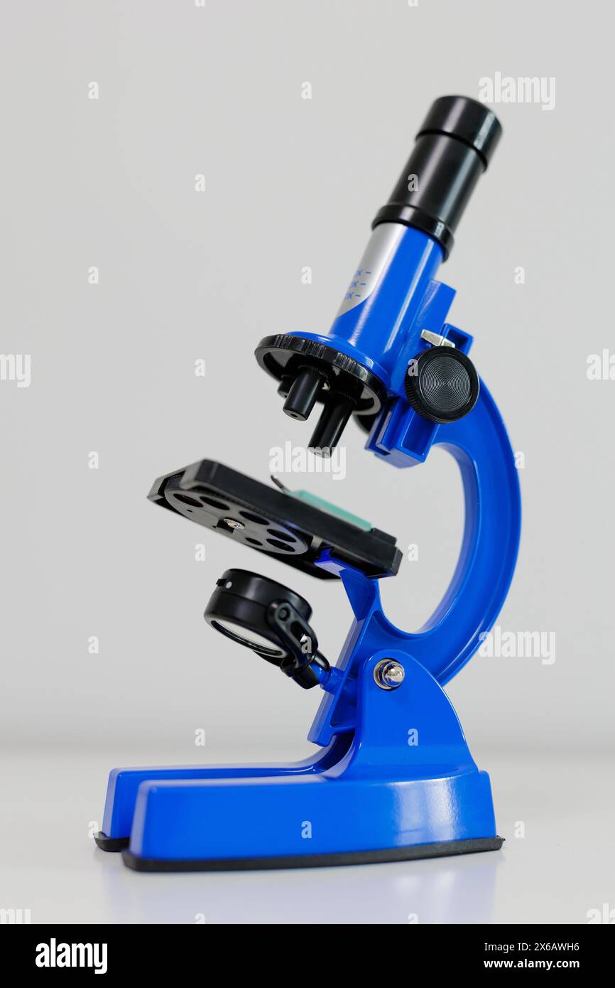 Side view of blue metal microscope on white table Stock Photo - Alamy