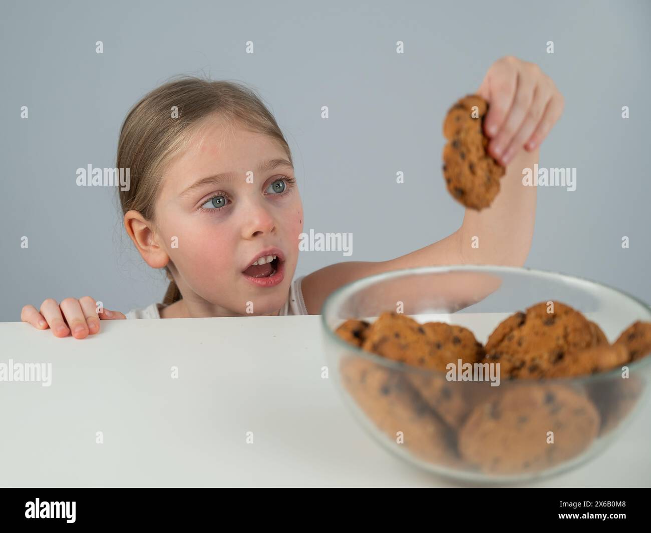 Little girl steals cookies from the table Stock Photo - Alamy