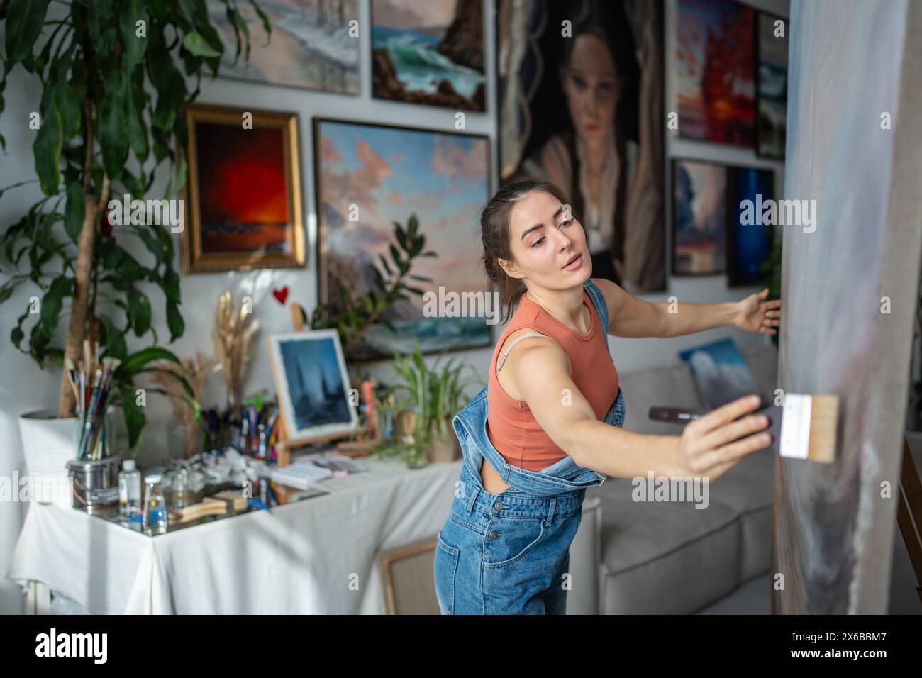 Female artist confidently wields wide brush, wiping canvas from dirt ...