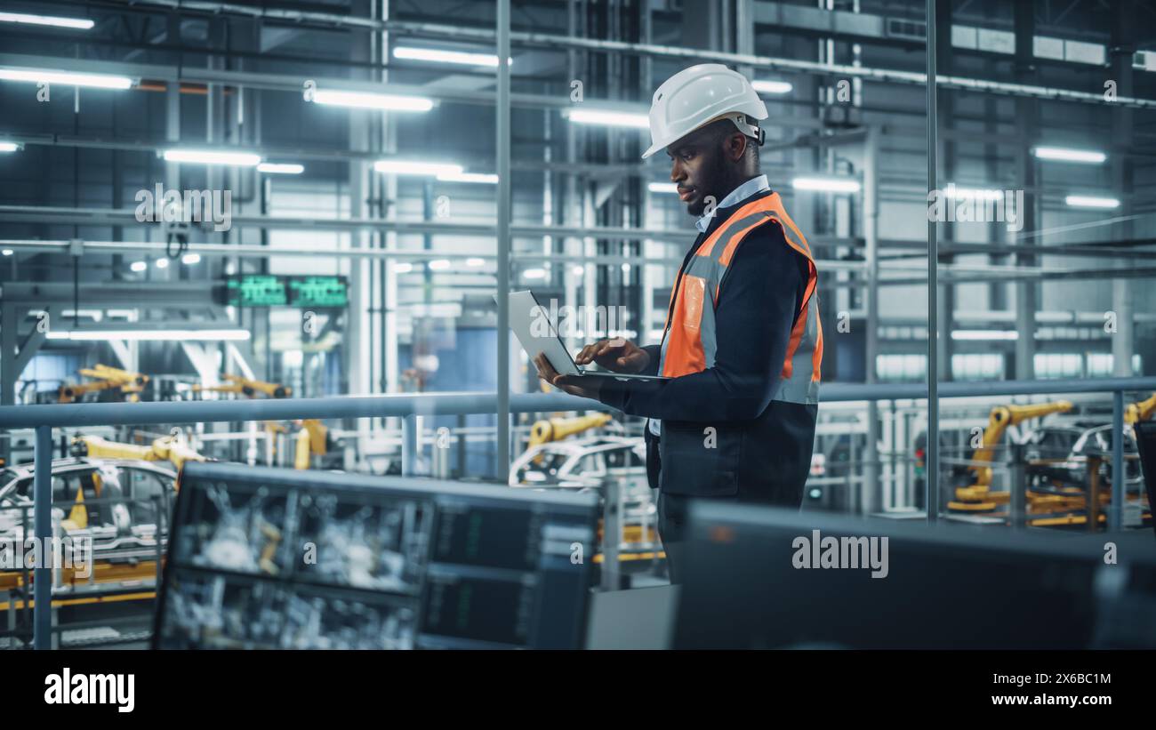 African American Engineer Using Laptop and Looking Out of the Office at ...