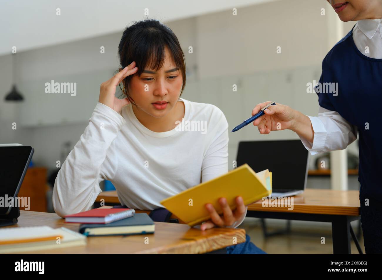 Mature lecturer helping female student struggling with schoolwork in a ...