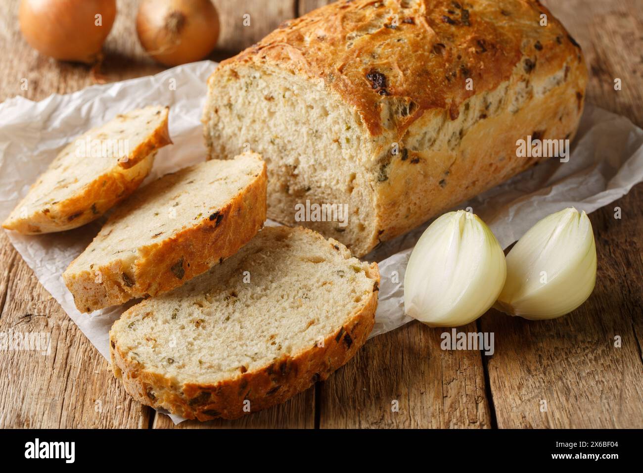 Traditional loaf of onion bread sliced close-up on parchment on a ...