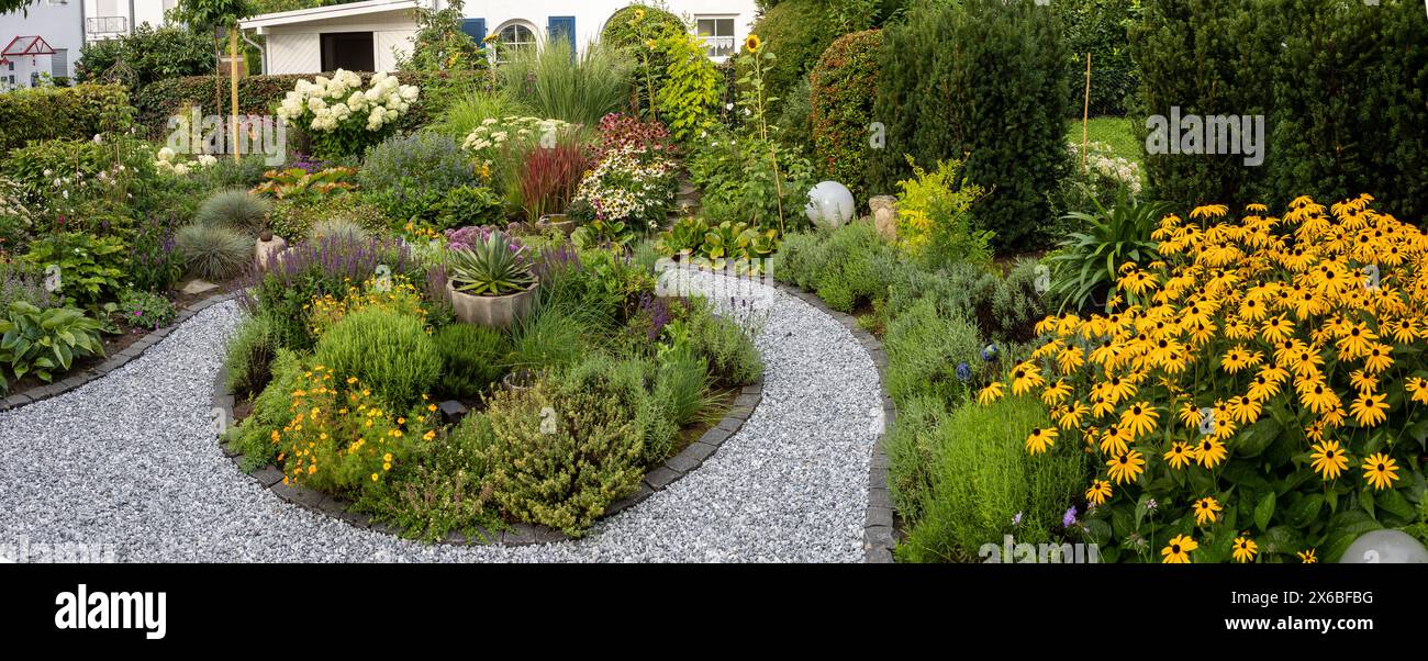 Panoramic garden view with a little path through a variety of flowers ...
