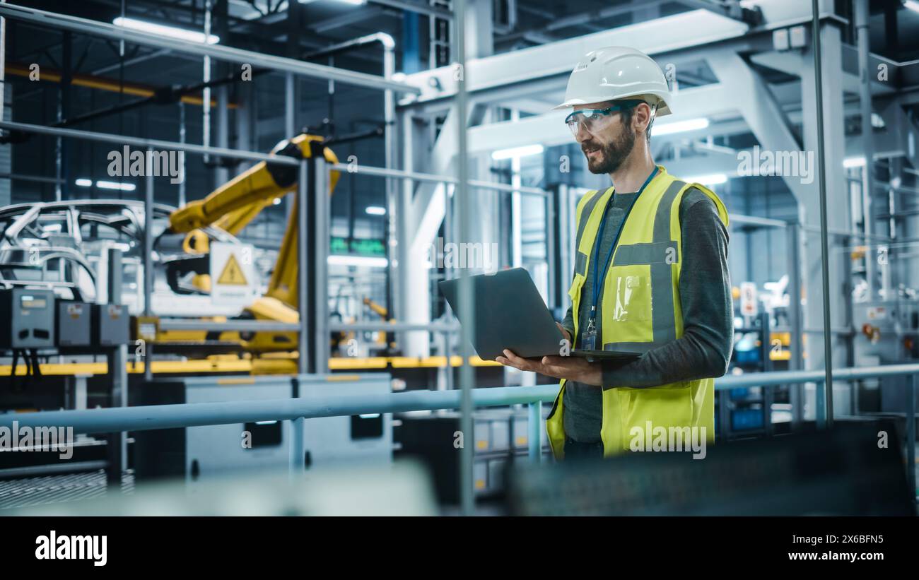 Car Factory: Male Automotive Engineer Wearing Hard Hat, Standing, Using ...