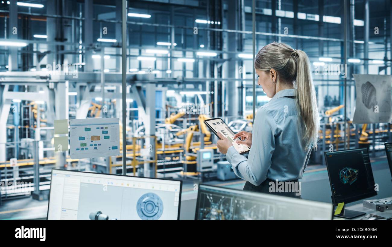 Car Factory Office Concept: Female Chief Automotive Engineer Using Tablet Computer to Develop ...