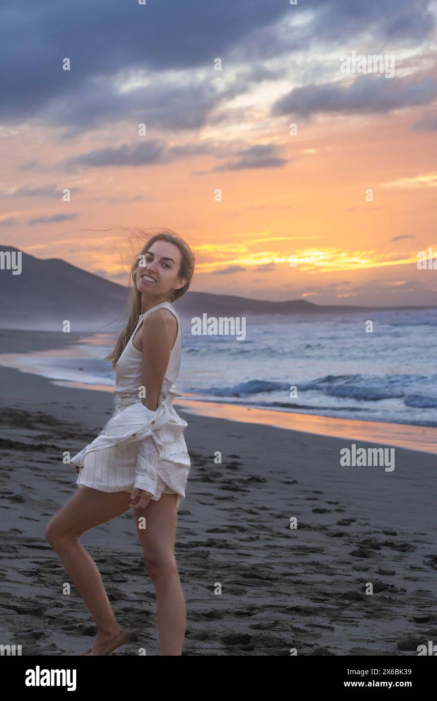 Young woman enjoys a peaceful sunset, with her smile radiating ...
