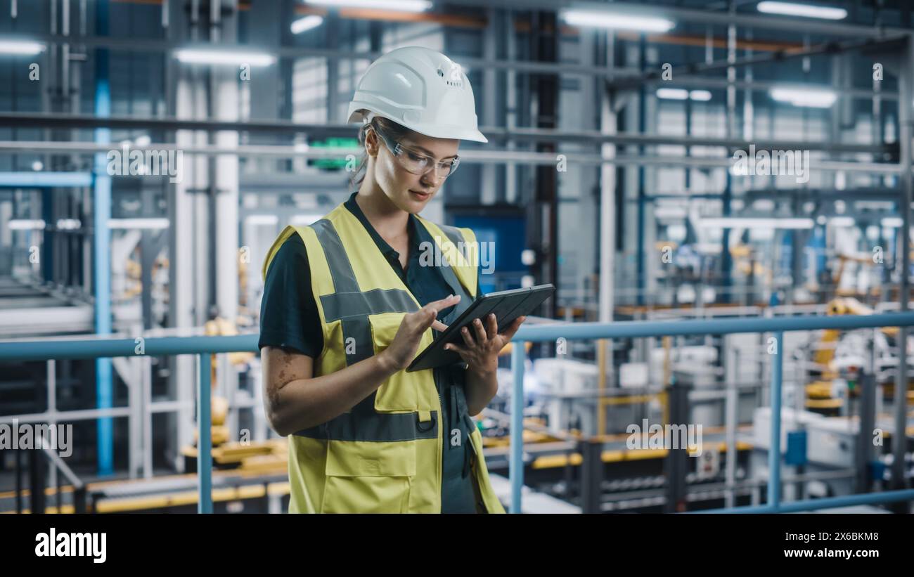 Female Car Factory Engineer in High Visibility Vest Using Laptop ...