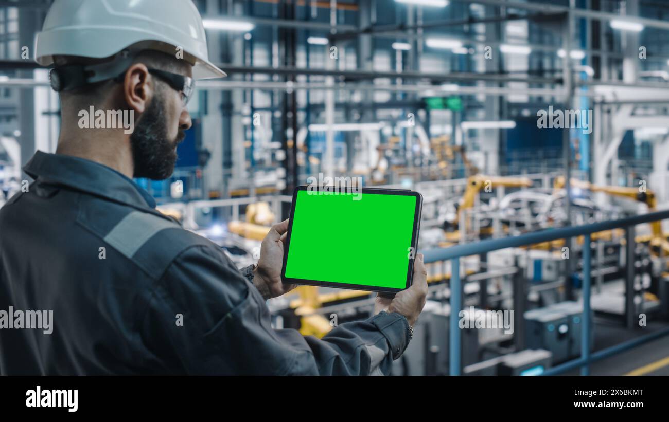 Car Factory Engineer in Work Uniform Using Tablet Computer with Green ...