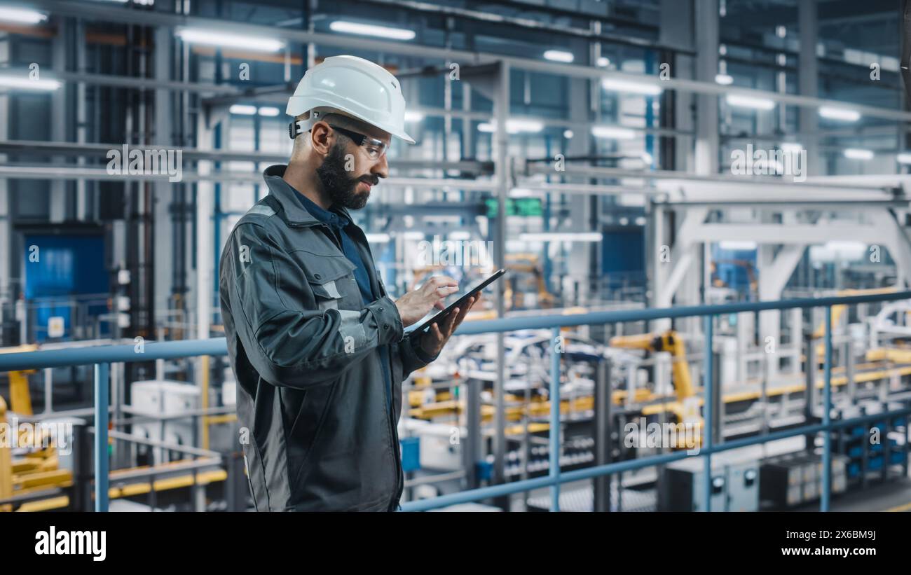 Car Factory Engineer in Work Uniform Using Tablet Computer. Automotive ...