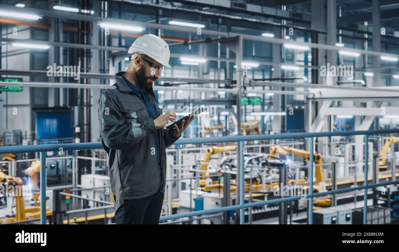 Car Factory Engineer in Work Uniform Using Tablet Computer. Automotive ...