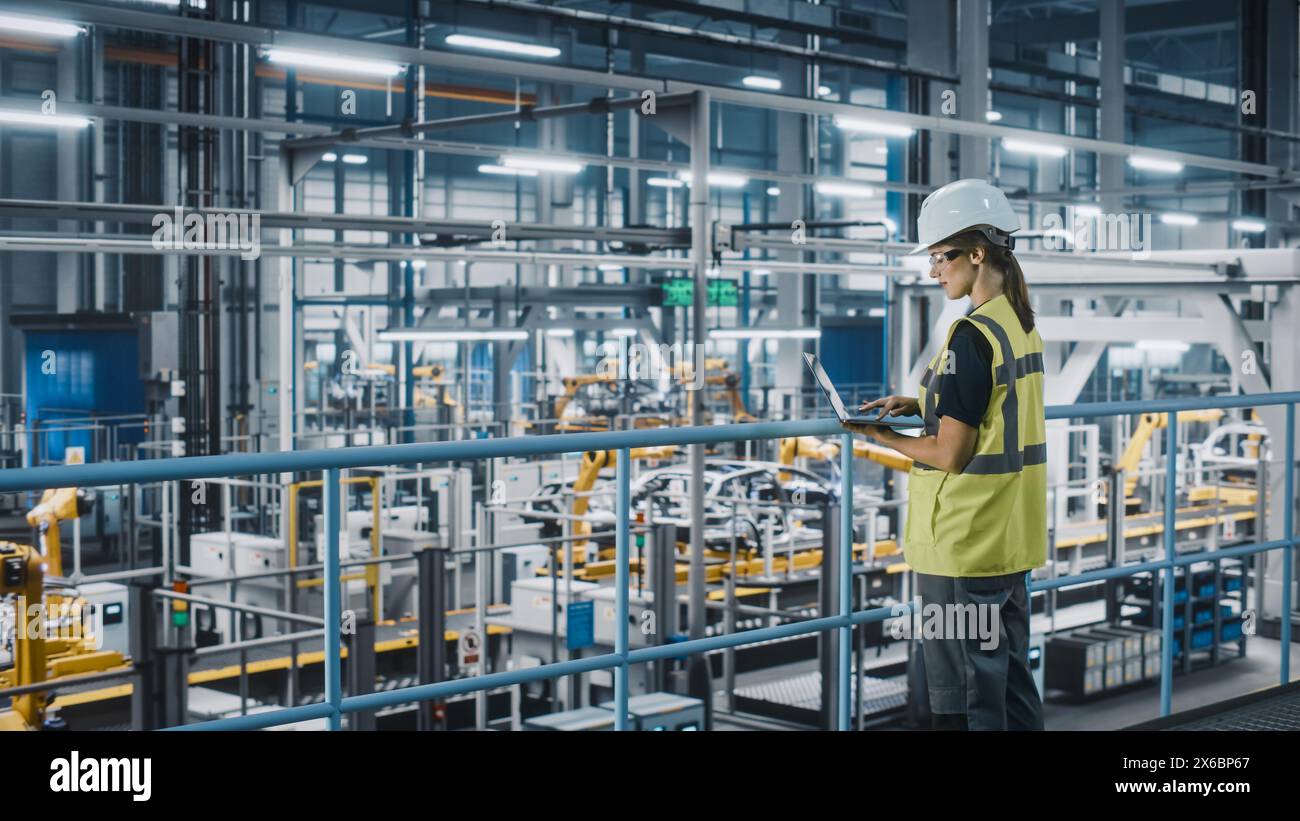 Female Car Factory Engineer in High Visibility Vest Using Laptop ...