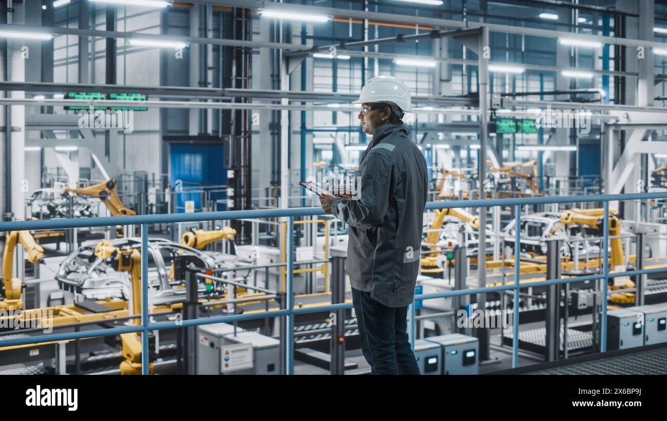 Car Factory Engineer in Work Uniform Using Tablet Computer. Automotive ...