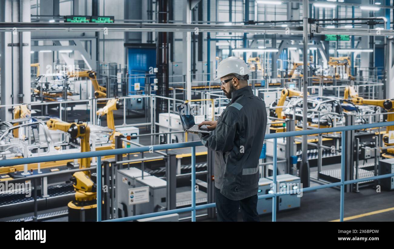 Car Factory Engineer in Work Uniform Using Laptop Computer. Automotive ...