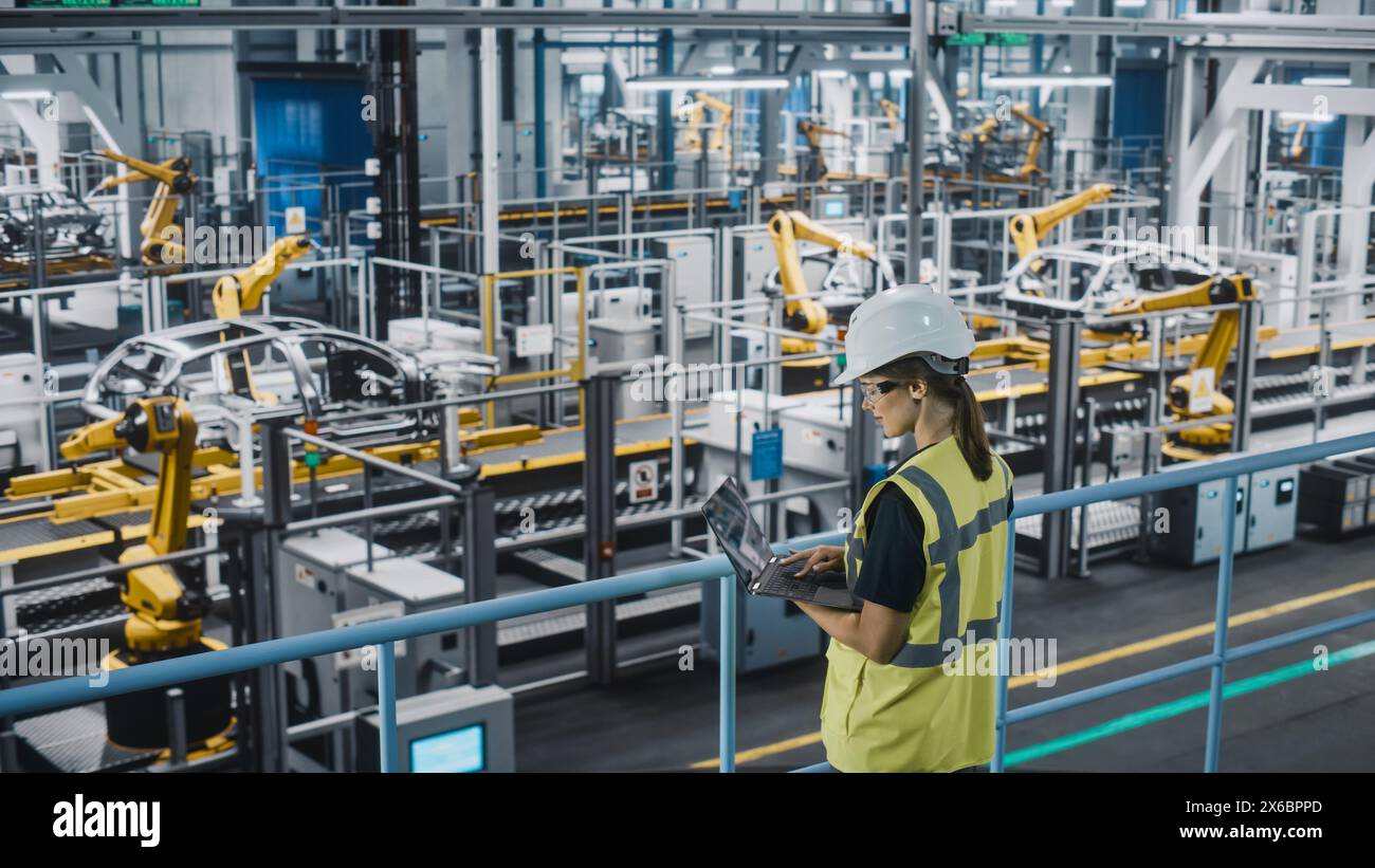 Female Car Factory Engineer in High Visibility Vest Using Laptop ...