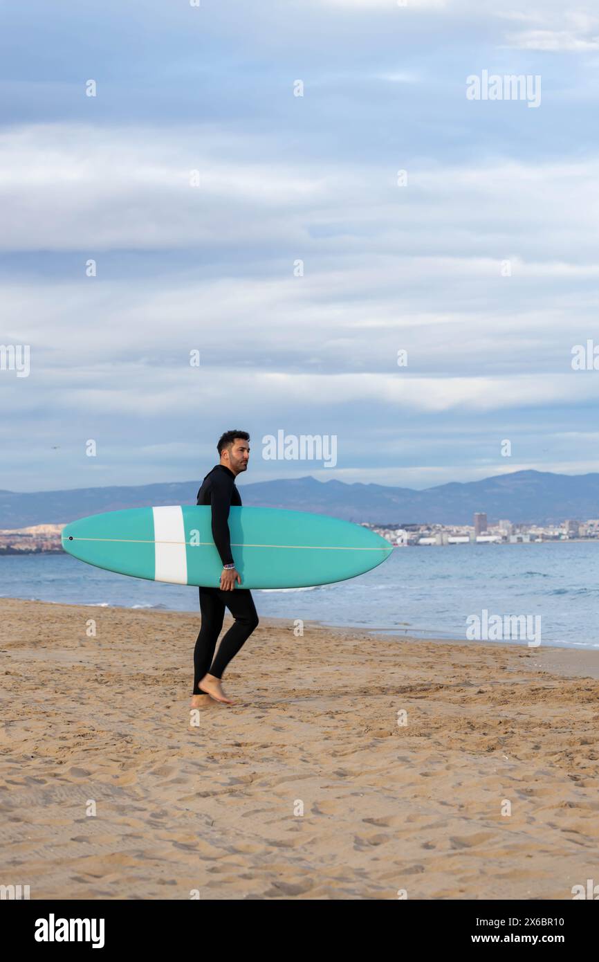 Surfer with surfboard and wetsuit entering the beach Stock Photo - Alamy
