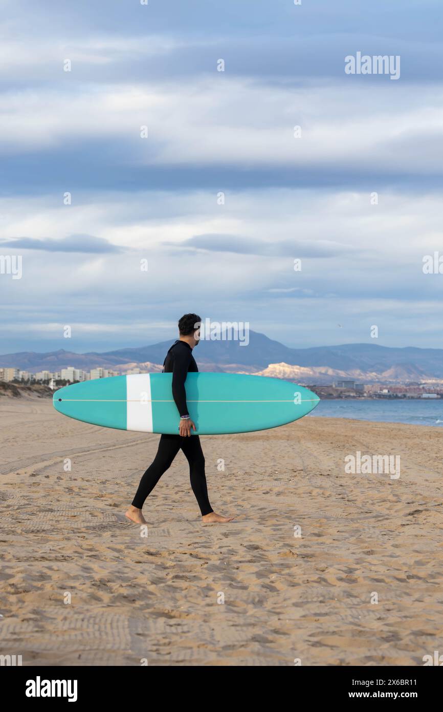 Surfer with surfboard and wetsuit entering the beach Stock Photo - Alamy