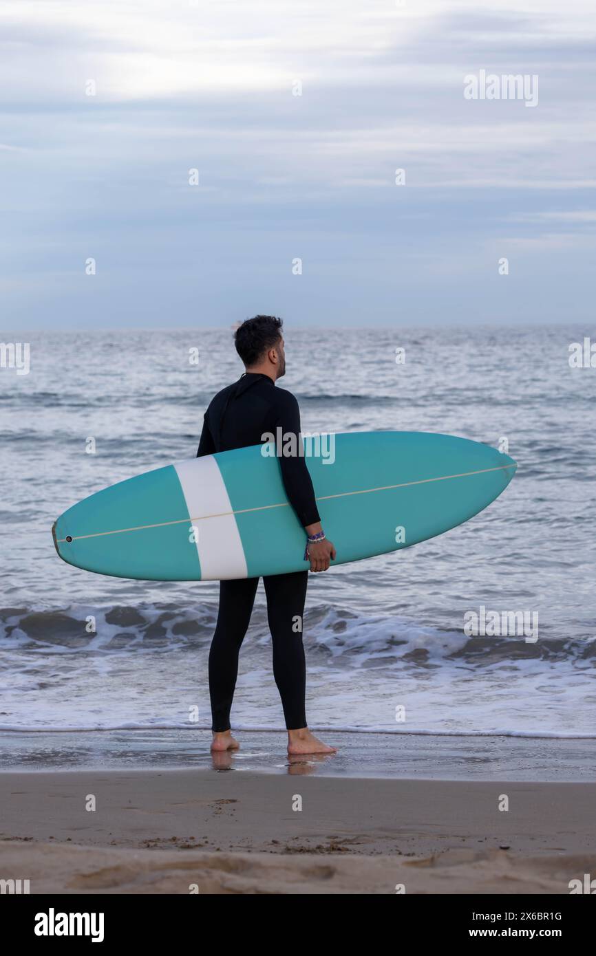 Surfer with surfboard and wetsuit entering the beach Stock Photo - Alamy