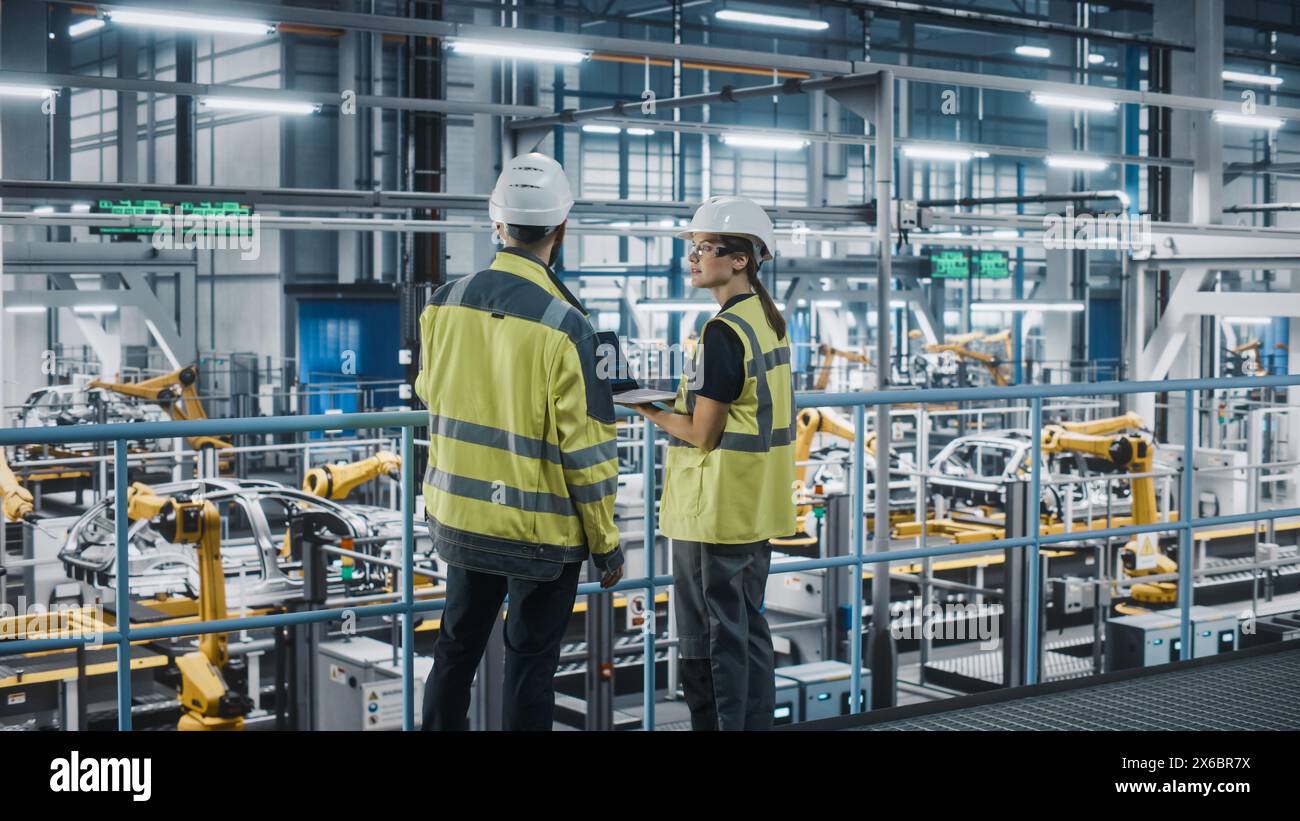 Male Specialist and Female Car Factory Engineer in High Visibility ...