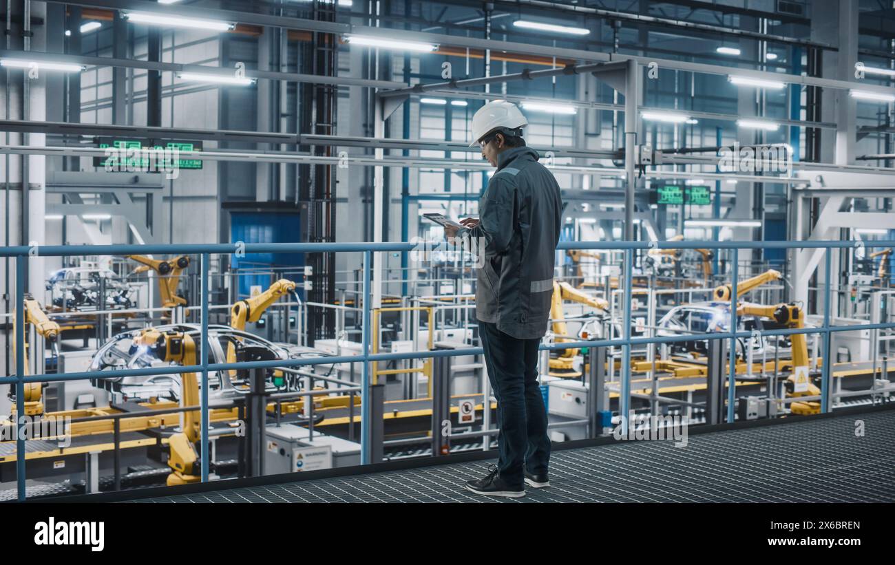 Car Factory Engineer in Work Uniform Using Tablet Computer. Automotive ...