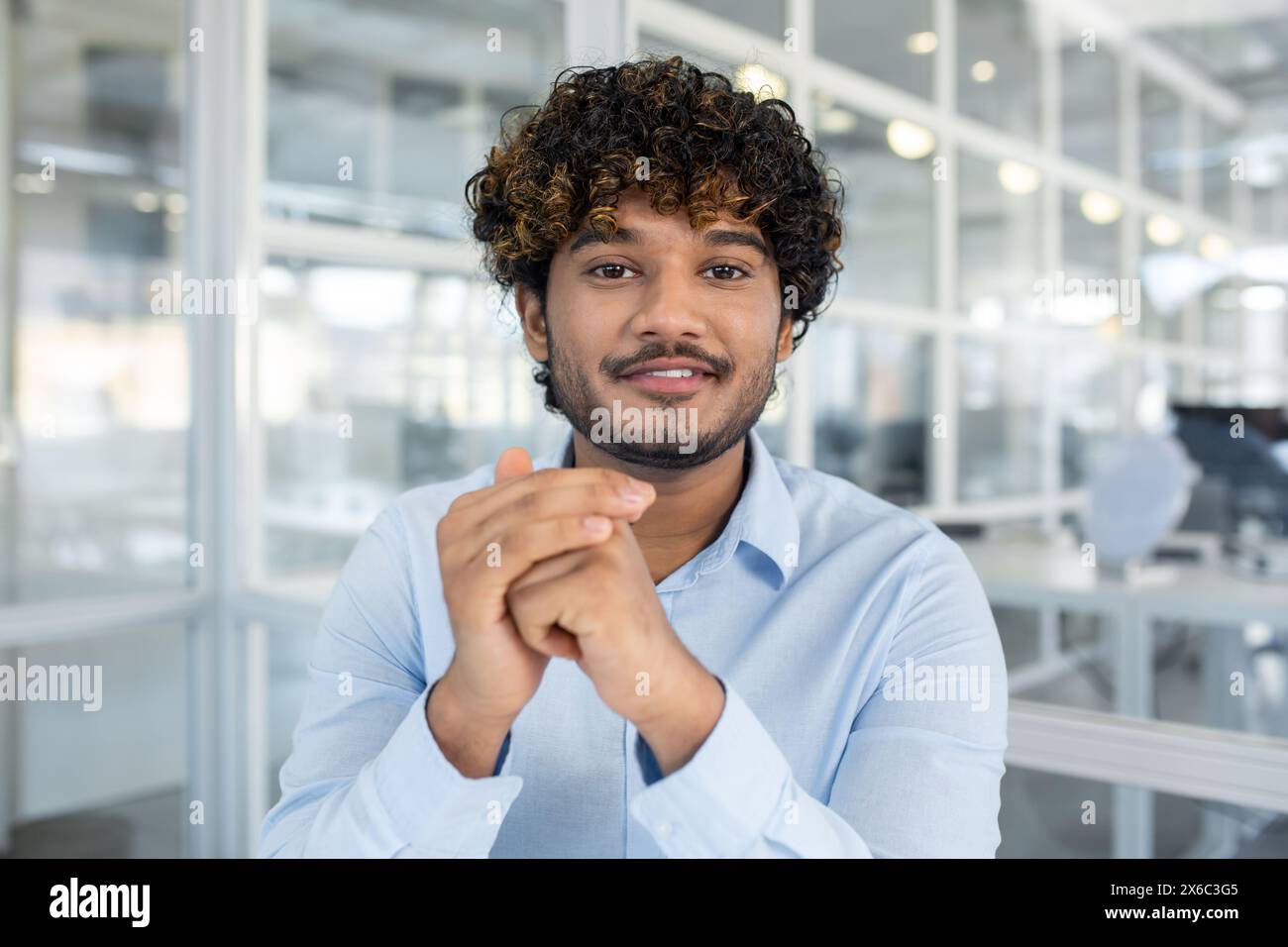 Portrait of a smiling young professional man sitting in a modern office ...