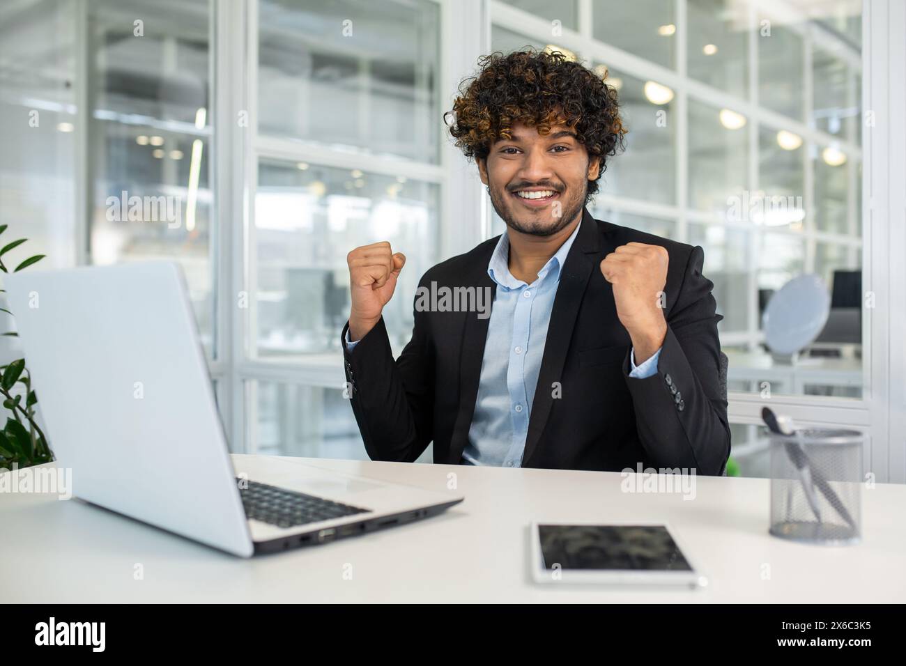 Cheerful businessman celebrating success at his desk in a modern office ...