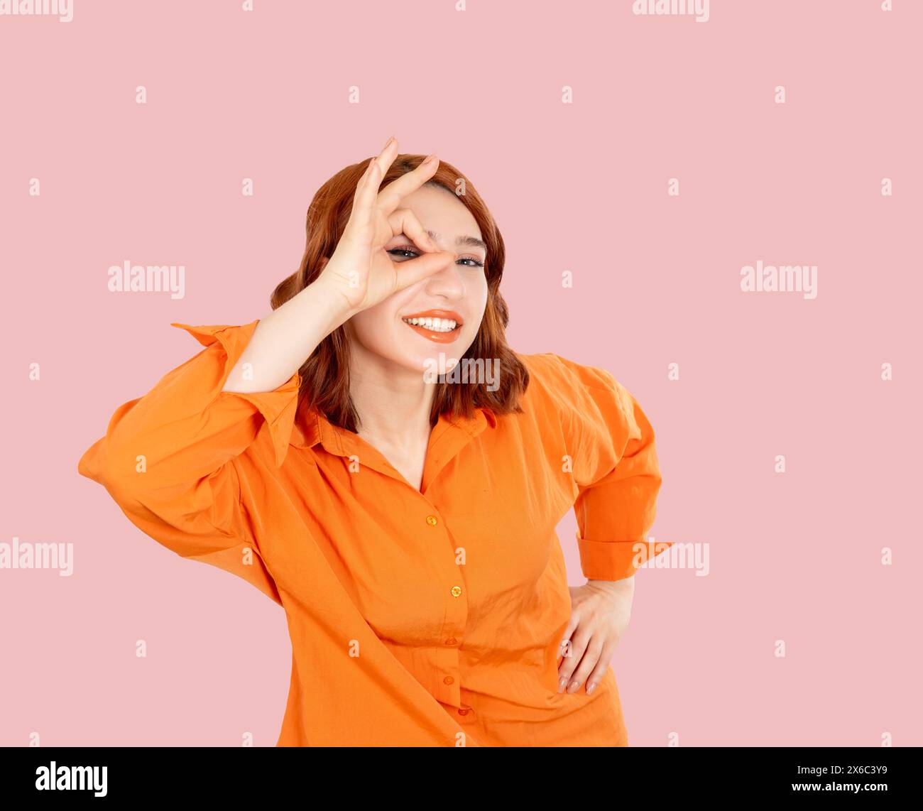 Happy smiling caucasian bob red hair woman eye looking through fingers ...