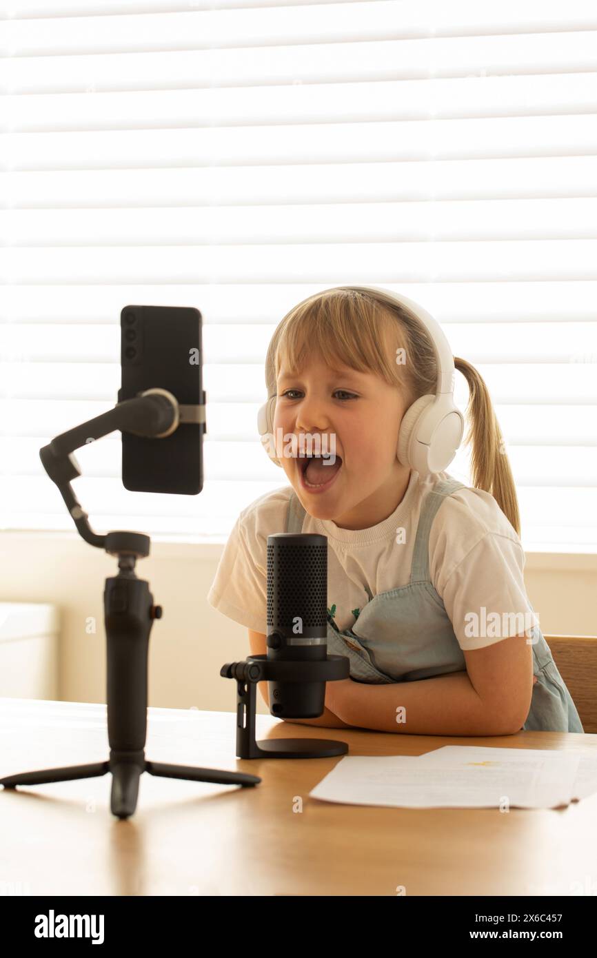 Young girl with headphones smiling during a solo podcast session ...