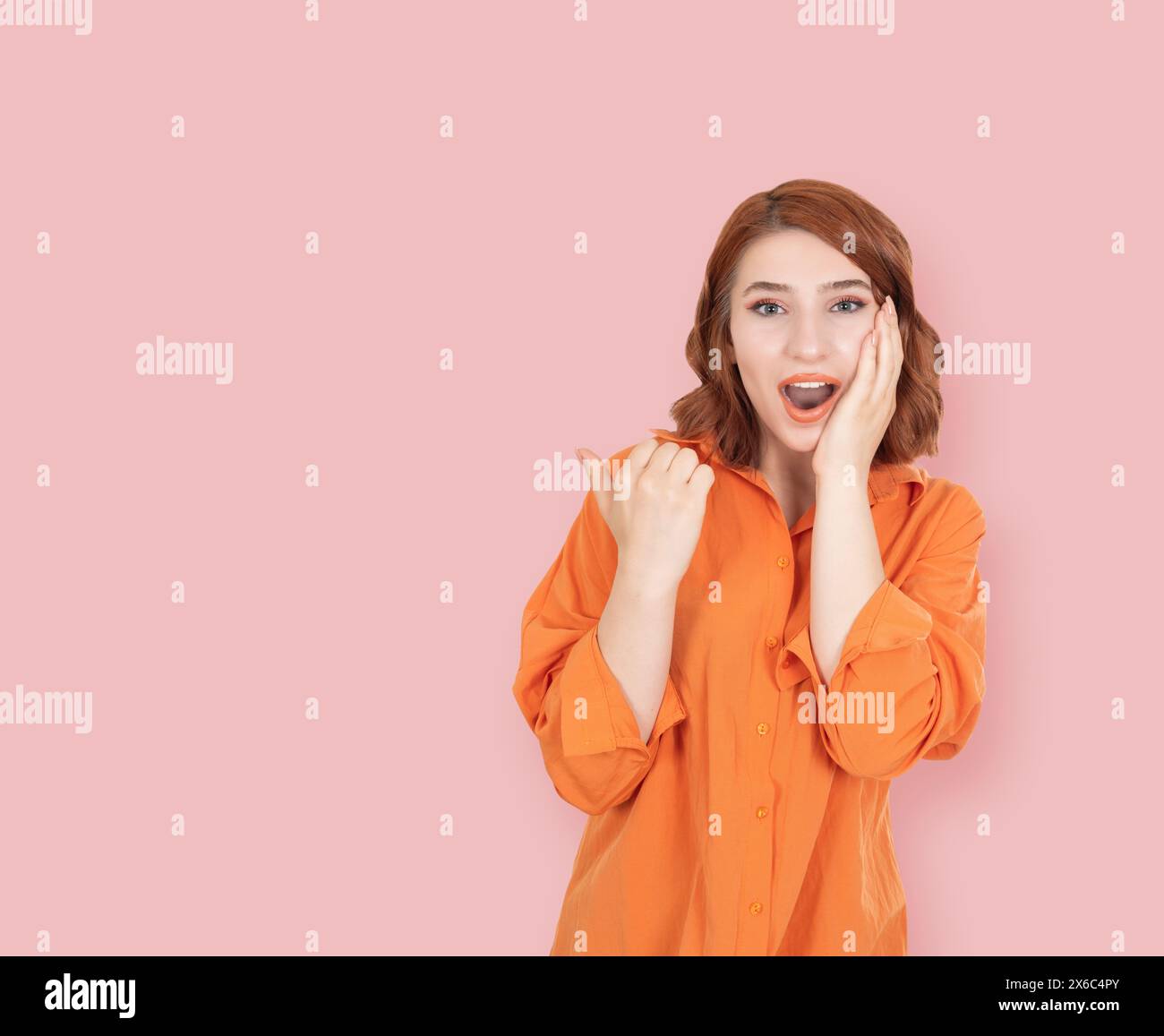 portrait of young red bob hair woman pointing thumb copy space. Shocked ...