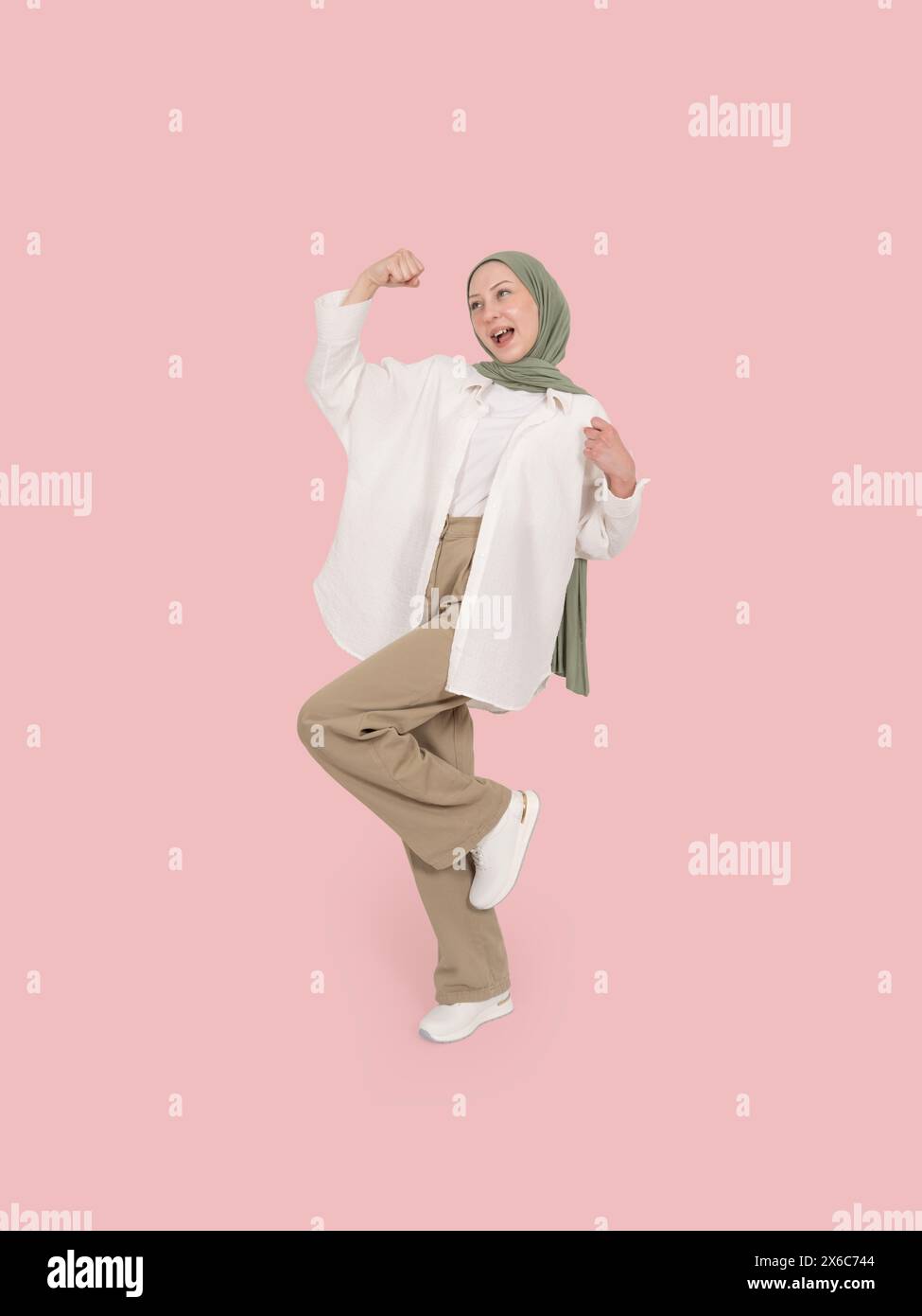 full body excited caucasian winner muslim woman posing over pink studio ...