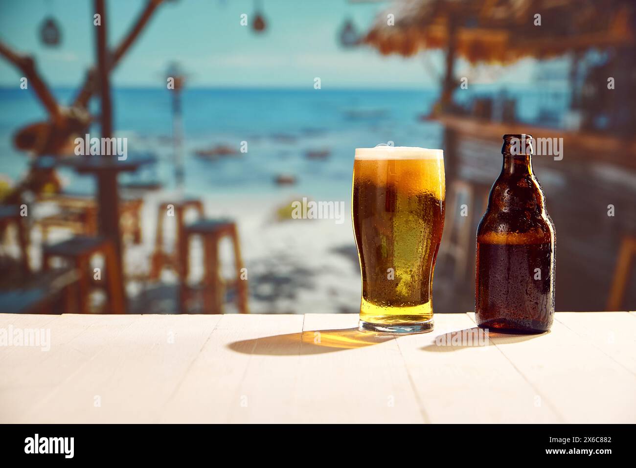 Glass with lager foamy chill beer and beer bottles standing on wooden ...