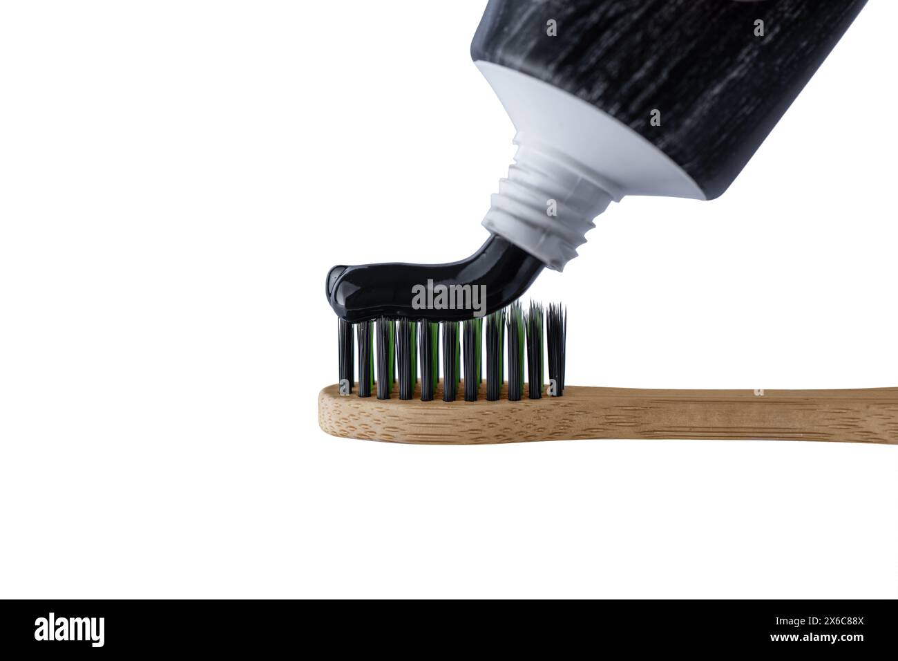 Putting charcoal toothpaste on bamboo toothbrush isolated on white ...
