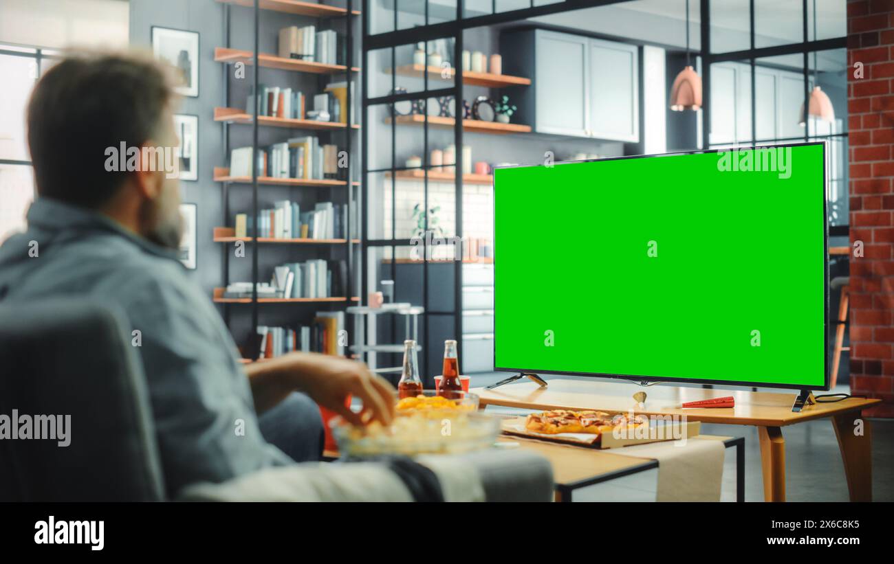 At Home Man Sitting on a Couch Watch Green Screen Chroma Key TV. Middle ...