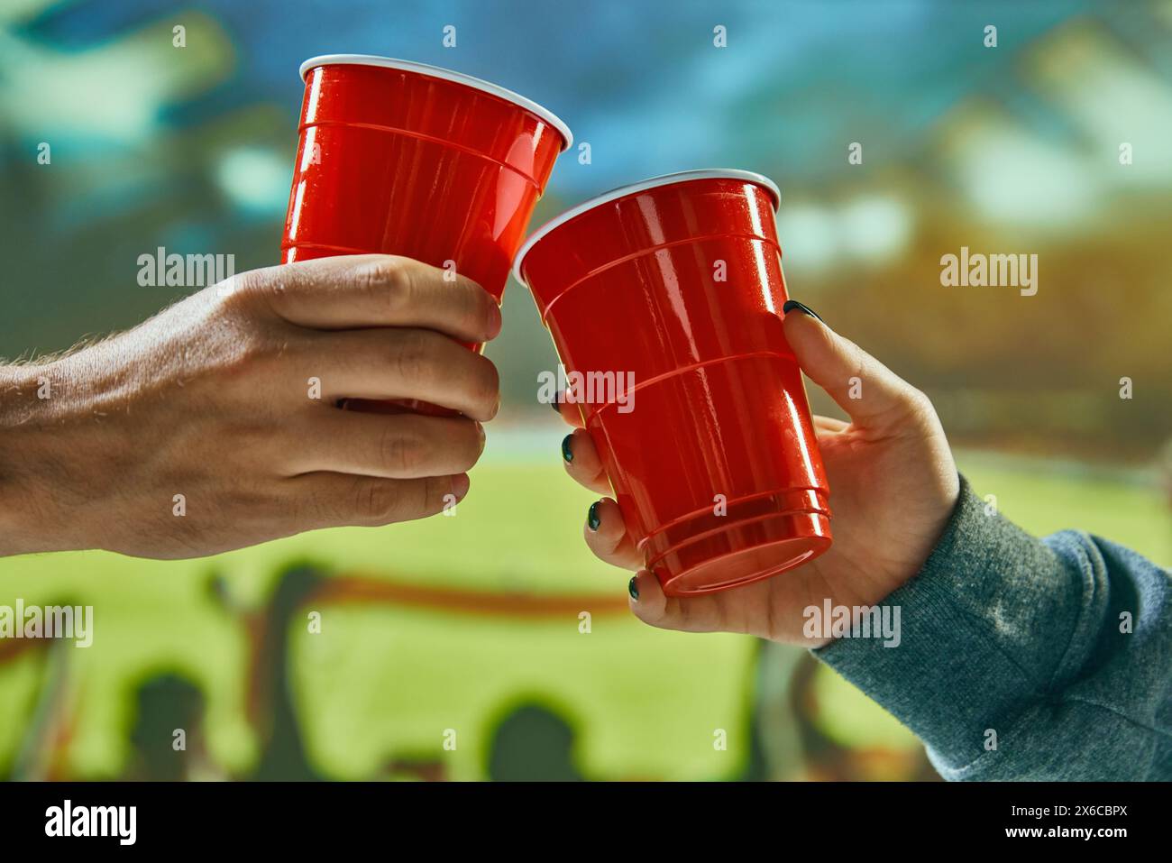 People clinking red mugs with beer at football stadium during match ...
