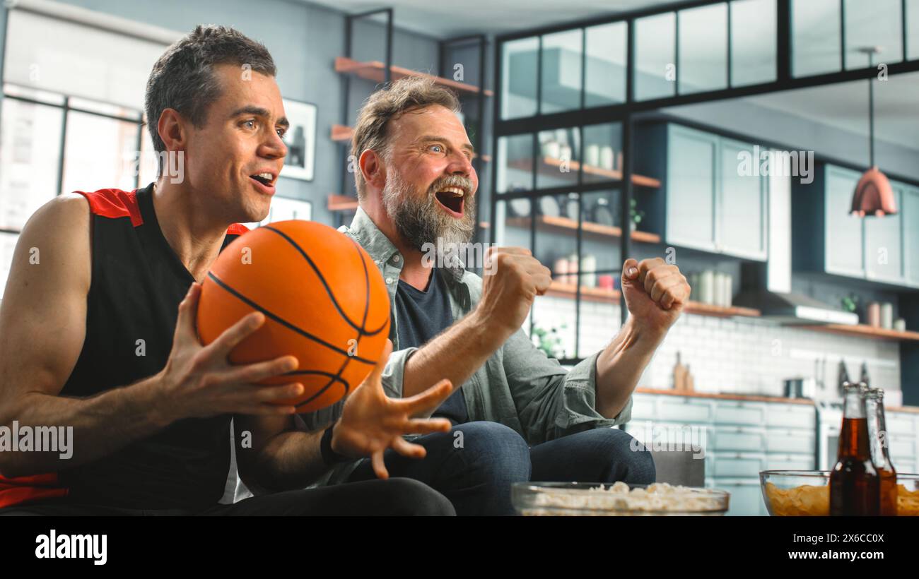 At Home Two Fans Sitting on a Couch Watch Basketball Game on TV ...
